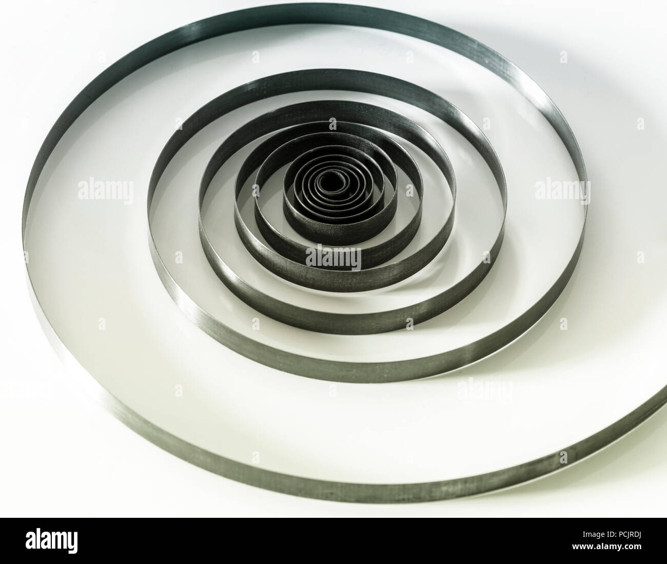 Spiral steel spring on a white mirror surface close-up Stock Photo - Alamy