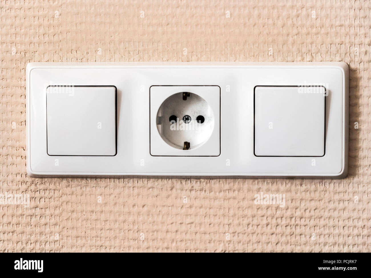 A block of light switches and a socket on a beige wall Stock Photo - Alamy