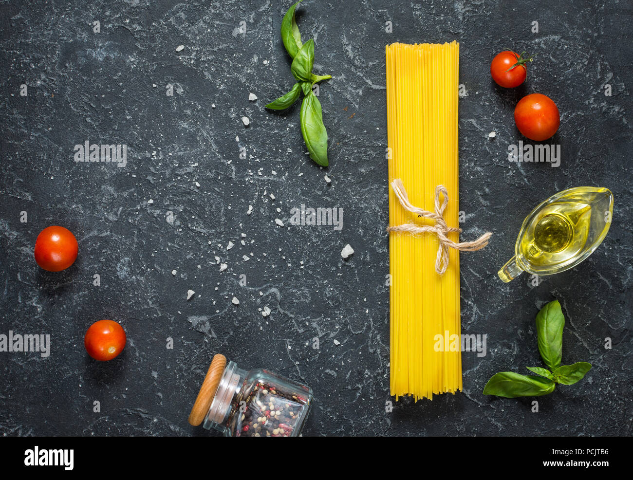 Bundle of Italian spaghetti pasta tied with string lying on dark stone ...