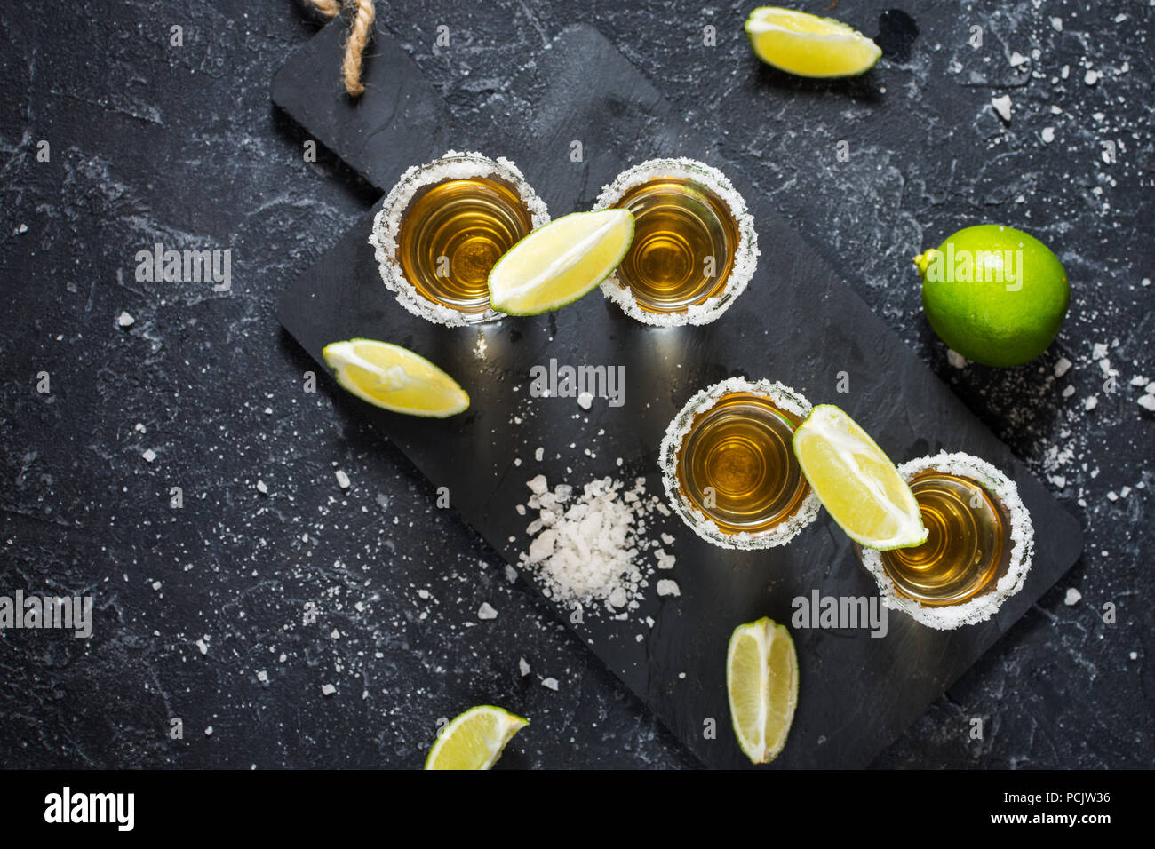 Mexican gold tequila with lime and salt on black stone background. Top ...