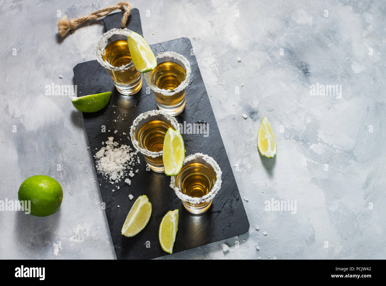 Mexican gold tequila with lime and salt on black stone background. Top ...