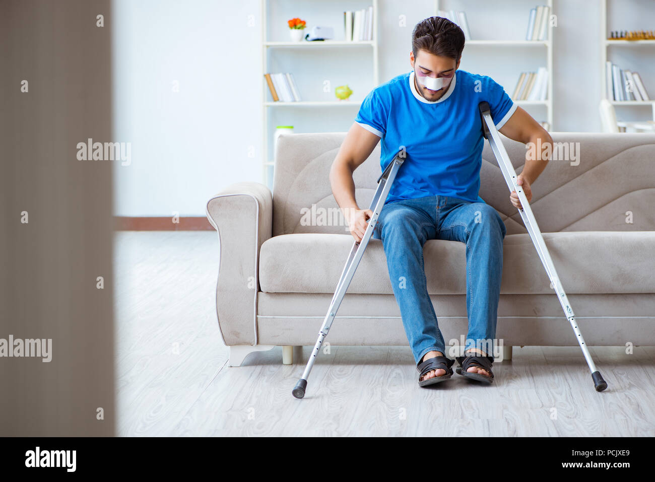 Injured man with crutches recovering at home Stock Photo - Alamy