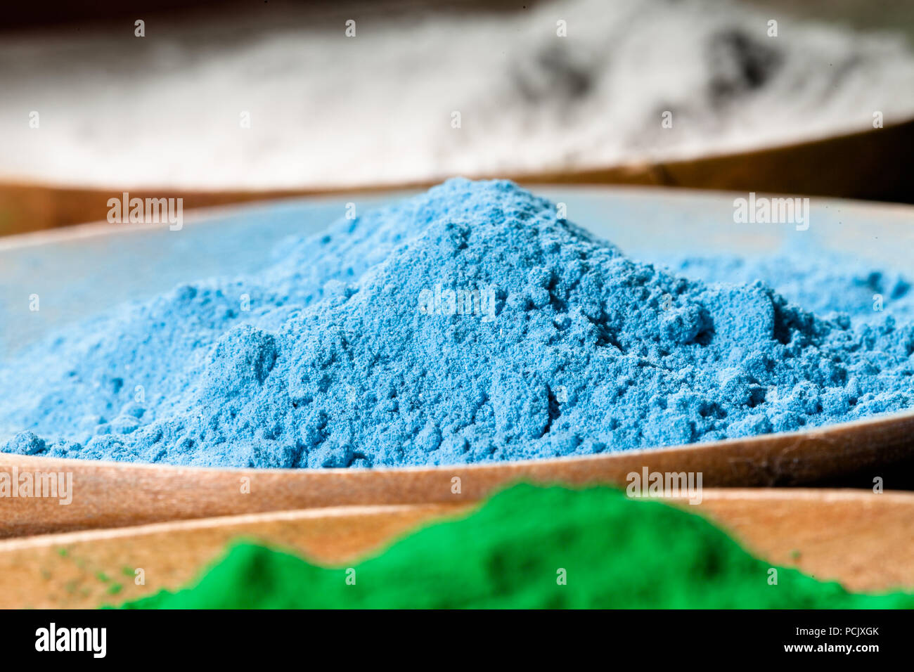 close up blue powder color on wooden spoon. colourful powder paint in ...