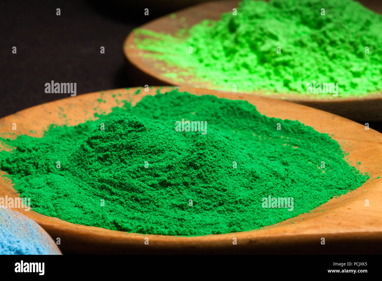 close up green powder color on wooden spoon. colourful powder paint in ...