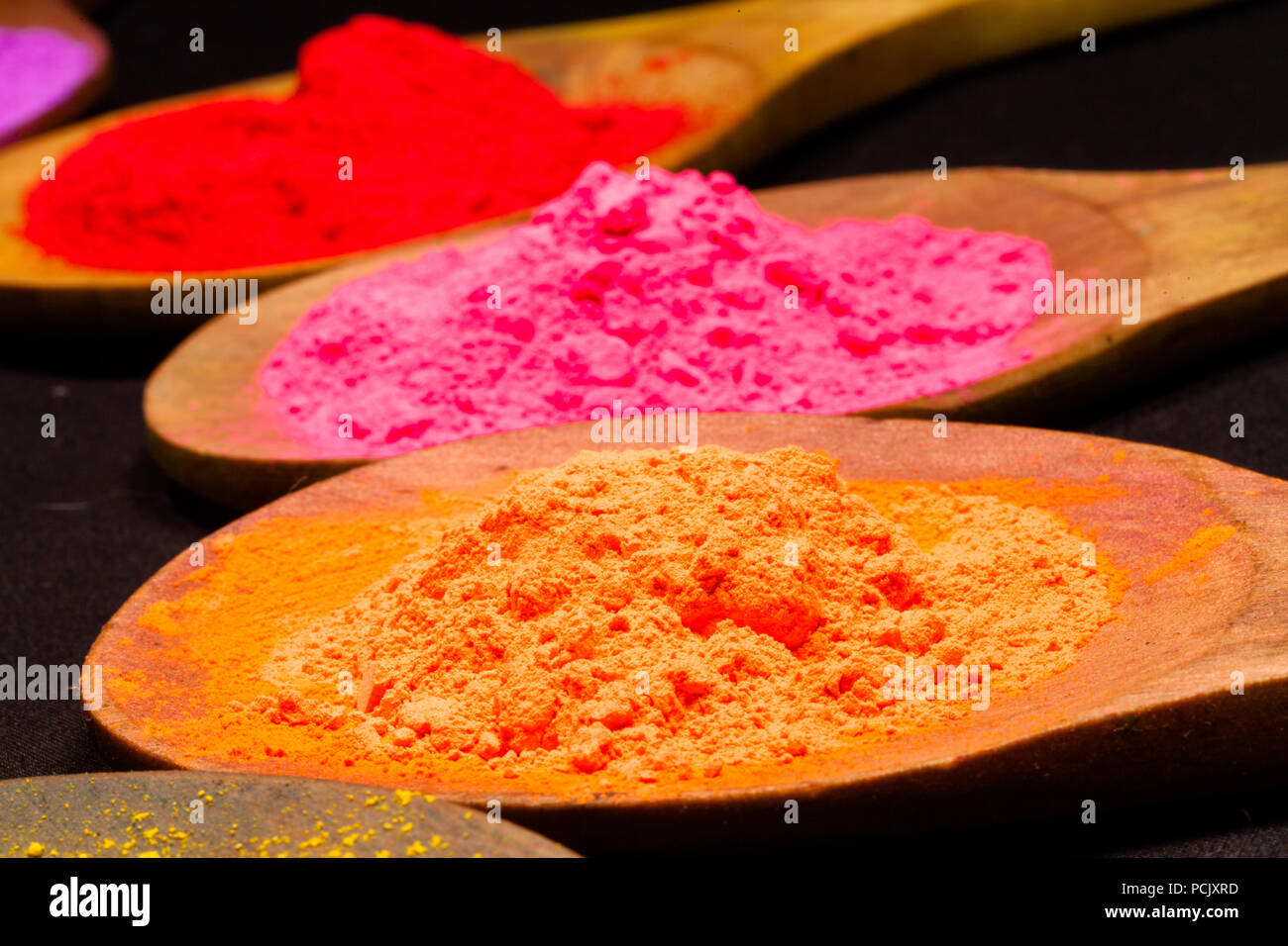 close up orange powder color on wooden spoon. colourful powder paint in ...