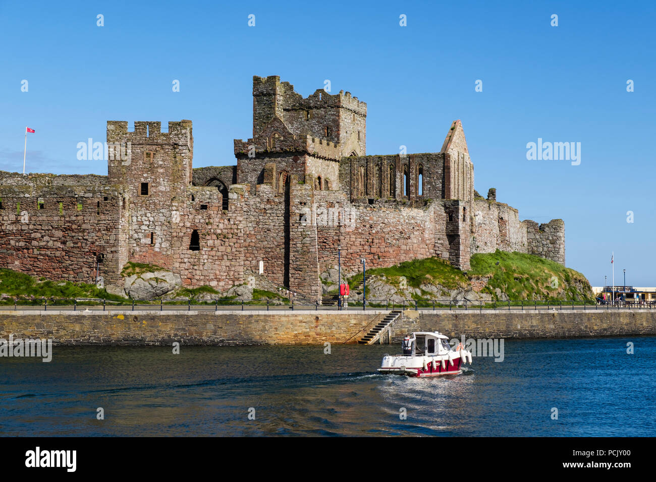 Peel castle ruins with boat heading out to sea from harbour. Peel, Isle ...