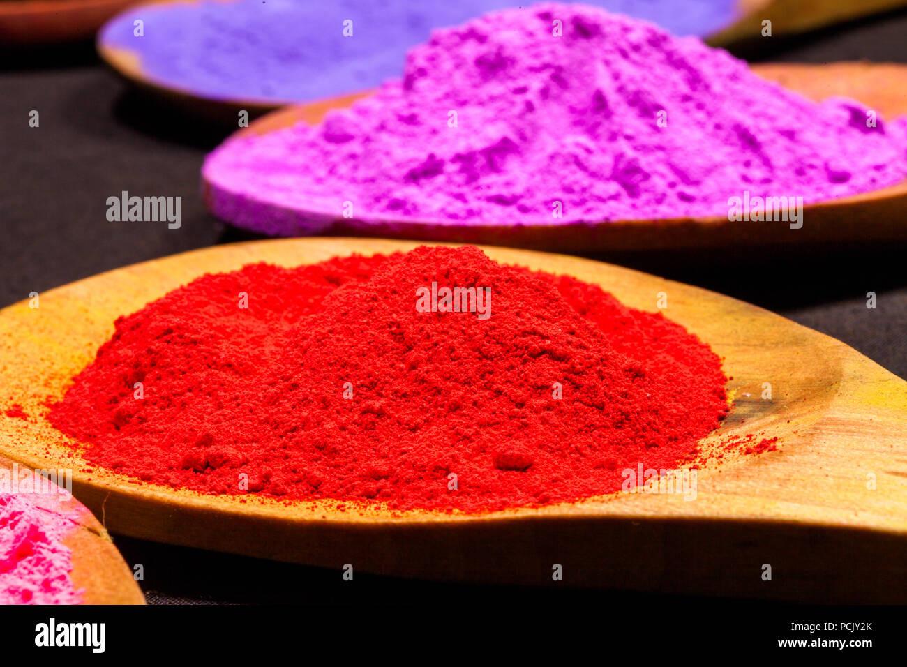 close up red powder color on wooden spoon. colourful powder paint in ...