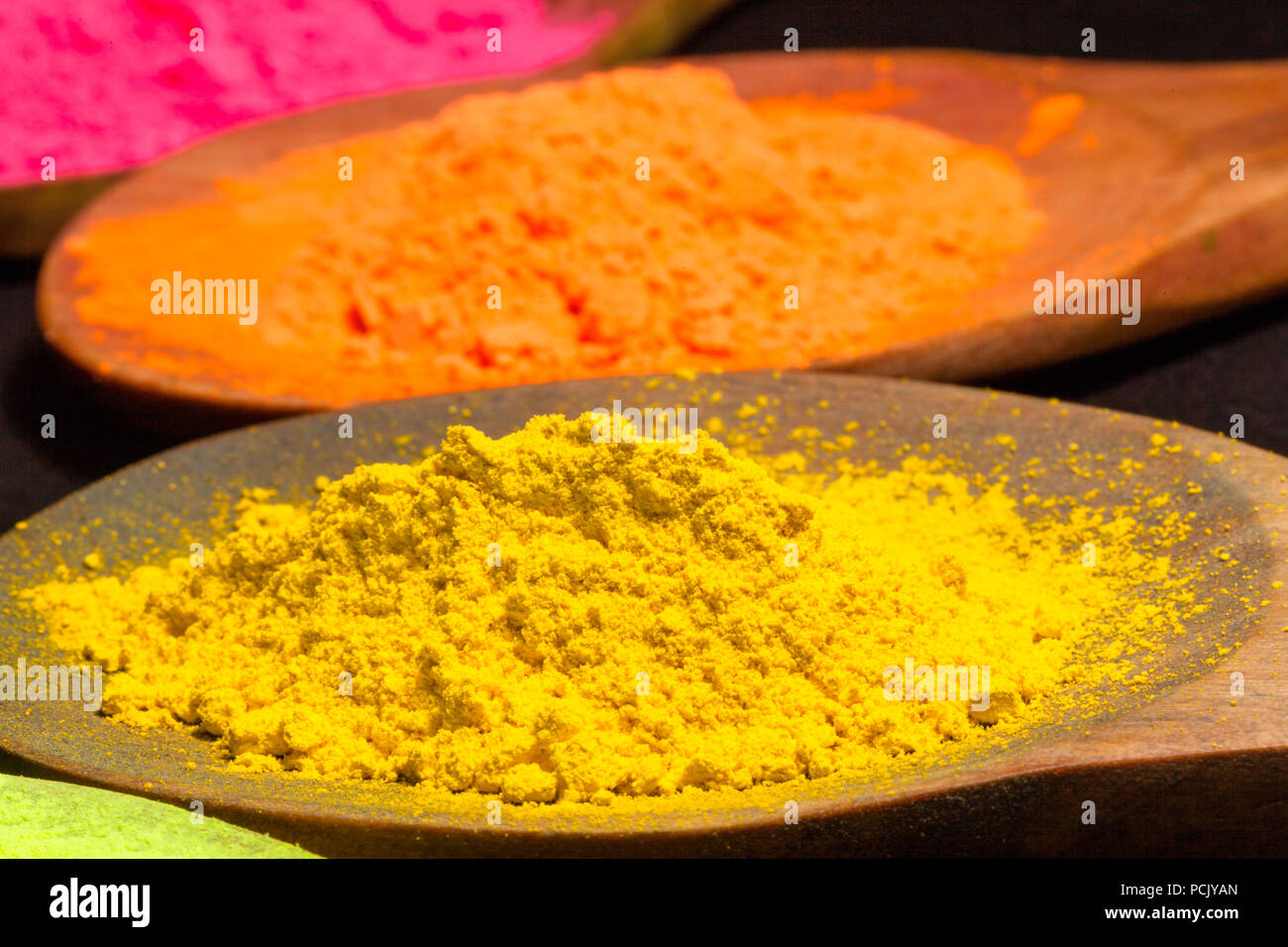 close up yellow powder color on wooden spoon. colourful powder paint in ...