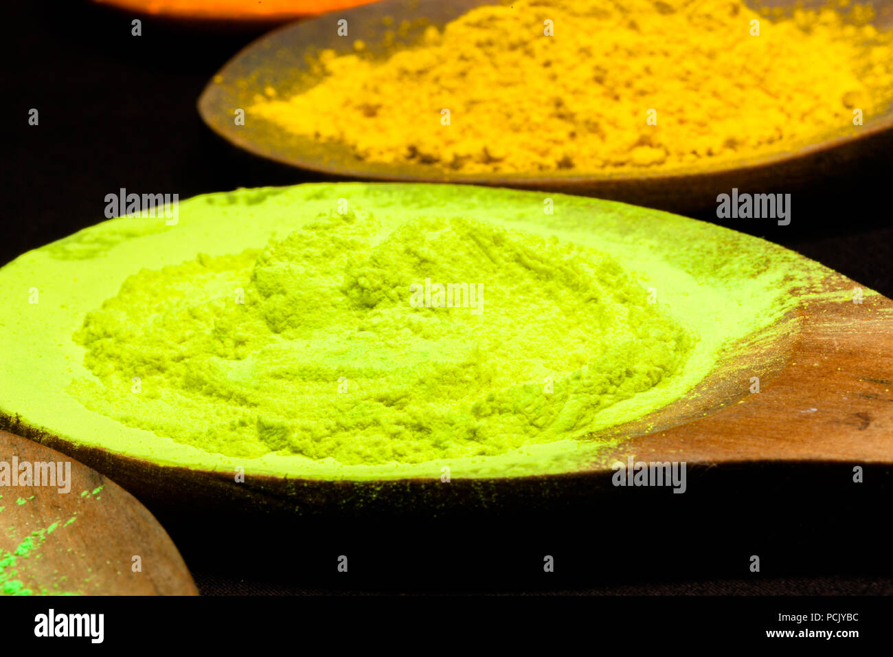 close up yellow powder color on wooden spoon. colourful powder paint in ...