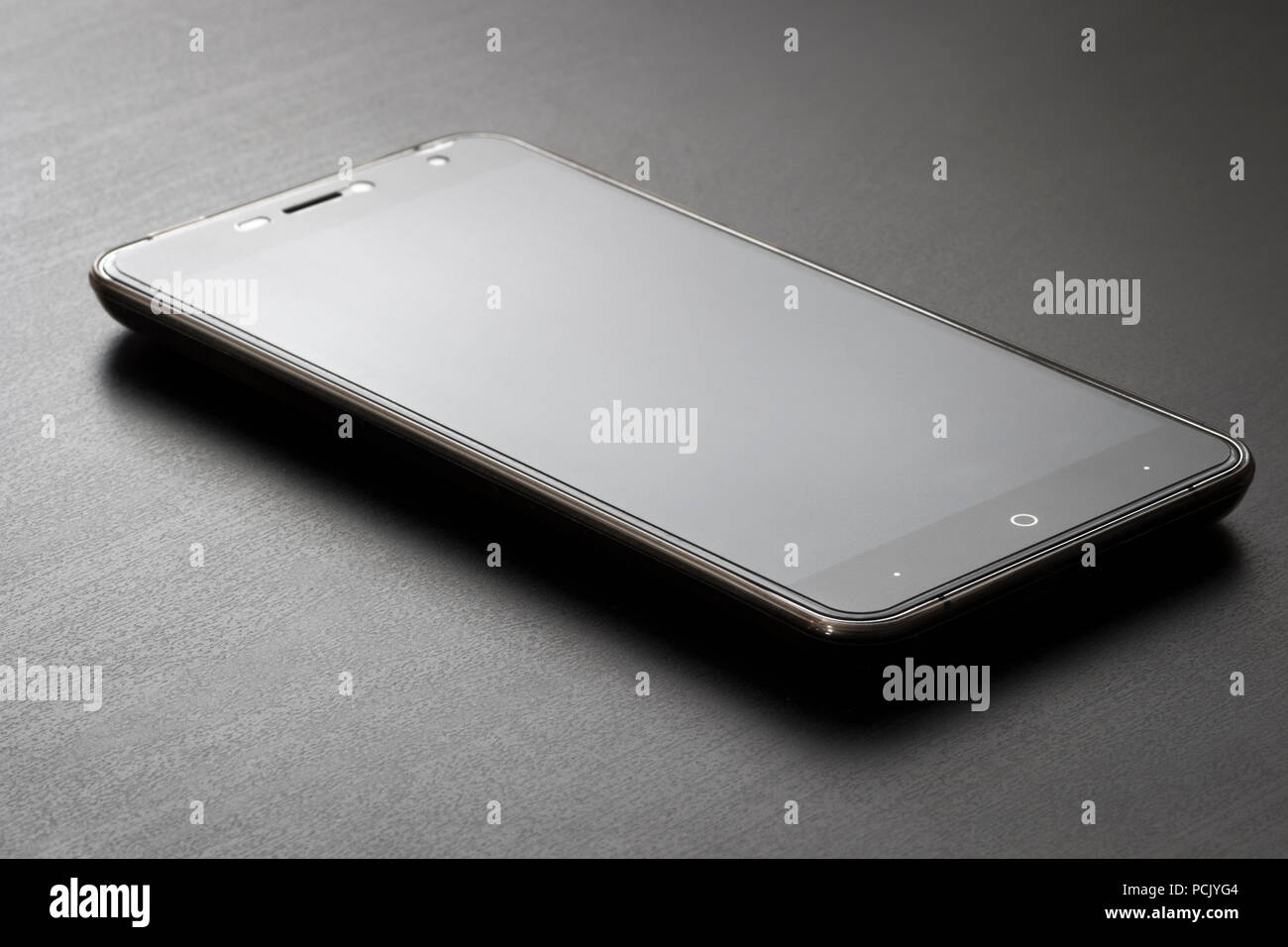 A smartphone rests on a black office desk close-up Stock Photo - Alamy