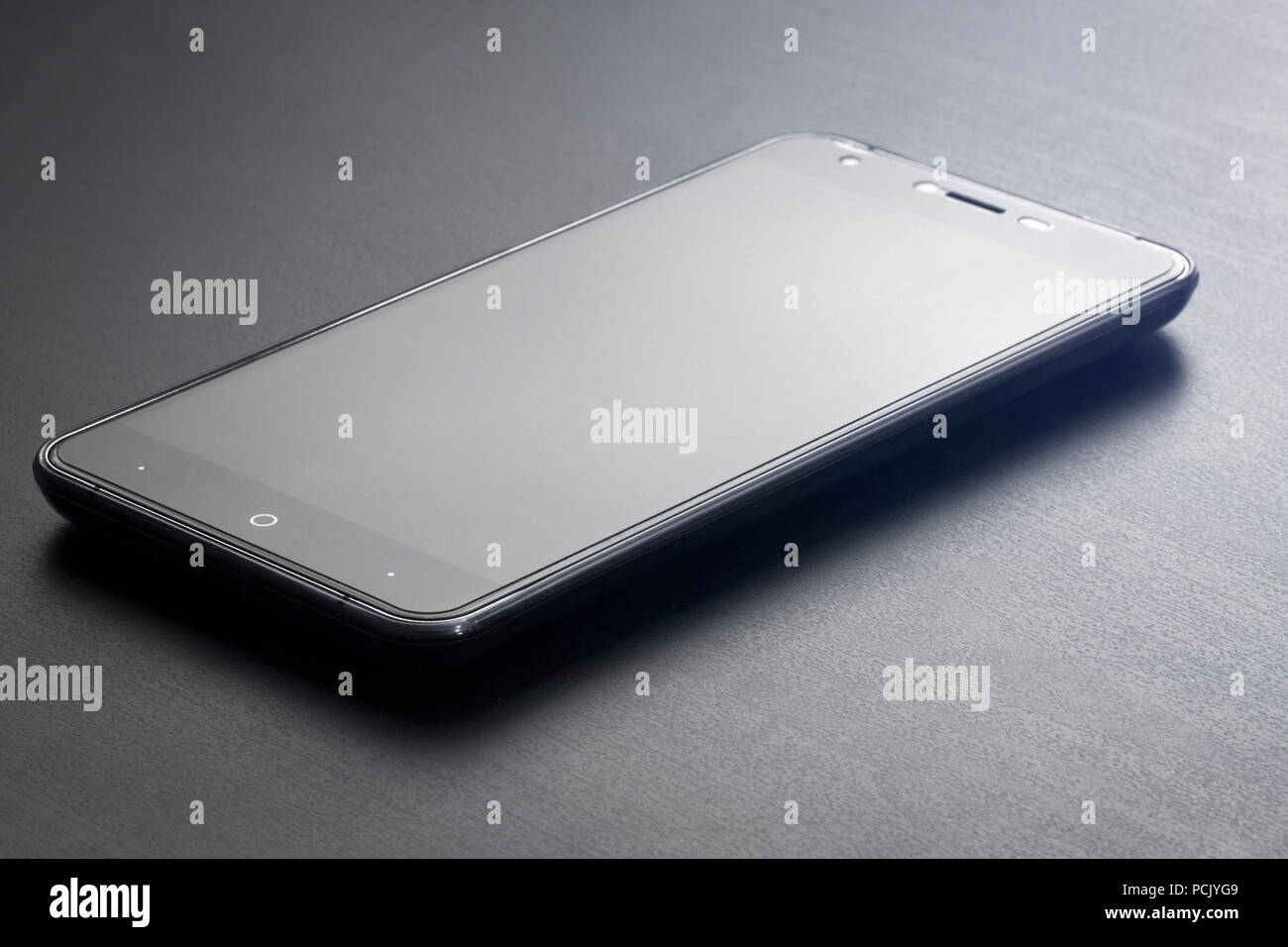 A smartphone rests on a black office desk close-up Stock Photo - Alamy