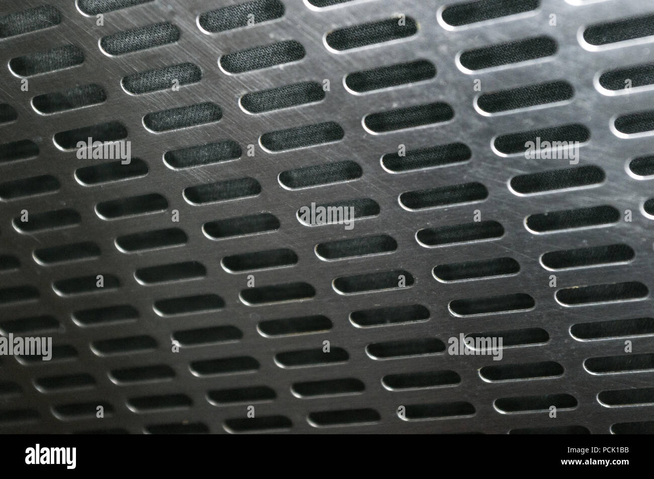 stainless steel grating with oblong holes on black background, close-up ...