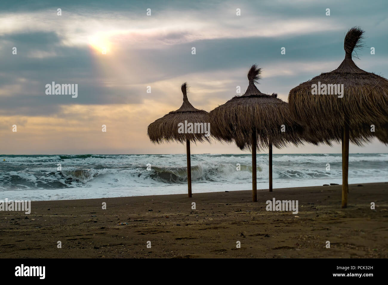 Straw beach umbrellas on stormy day Stock Photo - Alamy