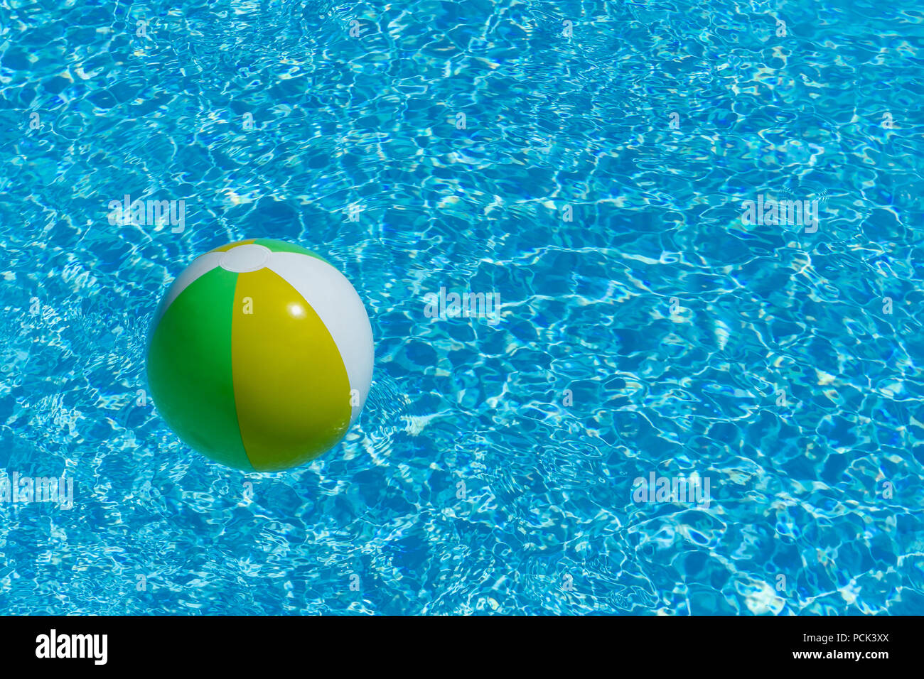 Inflatable multicolored ball floating on swimming pool water, with copy ...