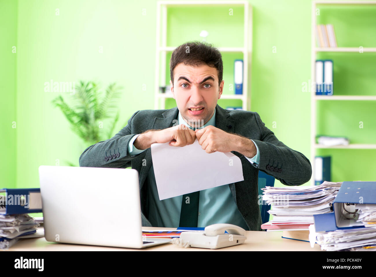 Businessman angry with excessive work sitting in the office Stock Photo ...