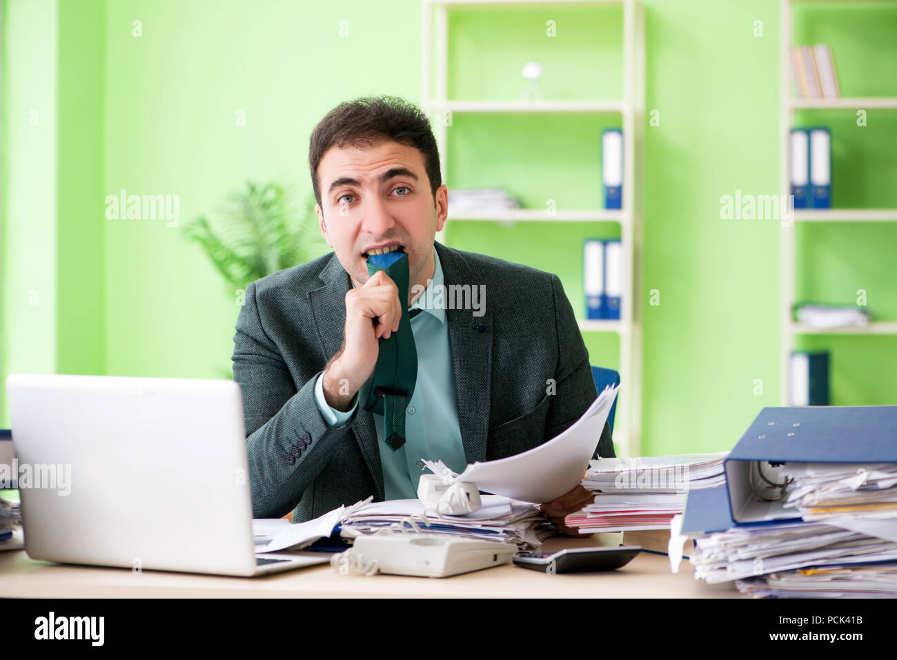 Businessman angry with excessive work sitting in the office Stock Photo ...