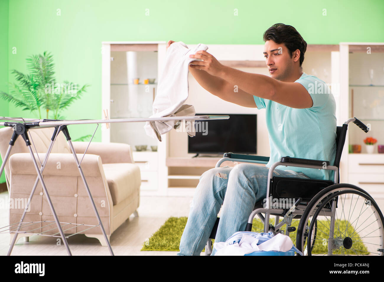Disabled man on wheelchair doing laundry Stock Photo - Alamy