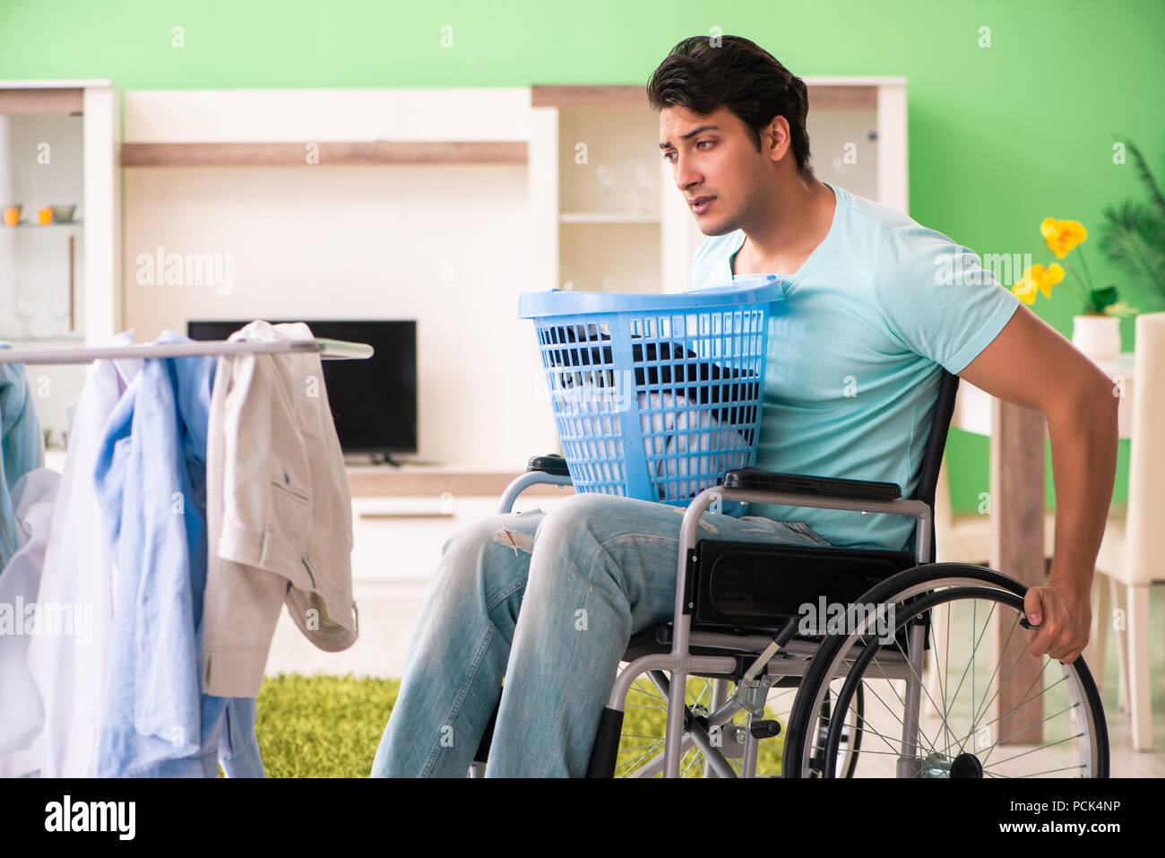 Disabled man on wheelchair doing laundry Stock Photo - Alamy