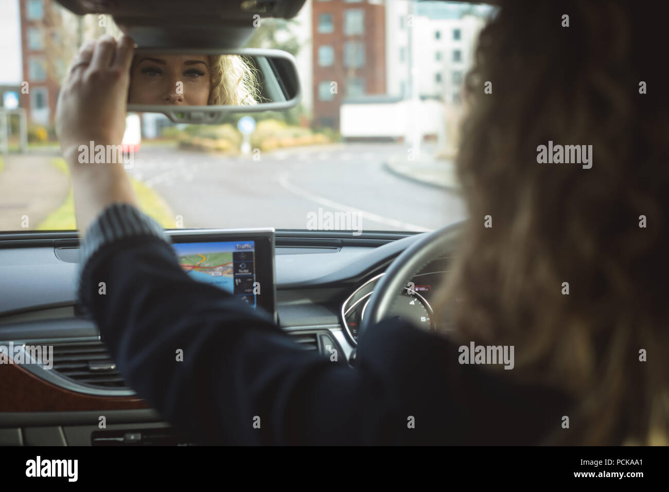 Female executive adjusting rear view mirror Stock Photo - Alamy