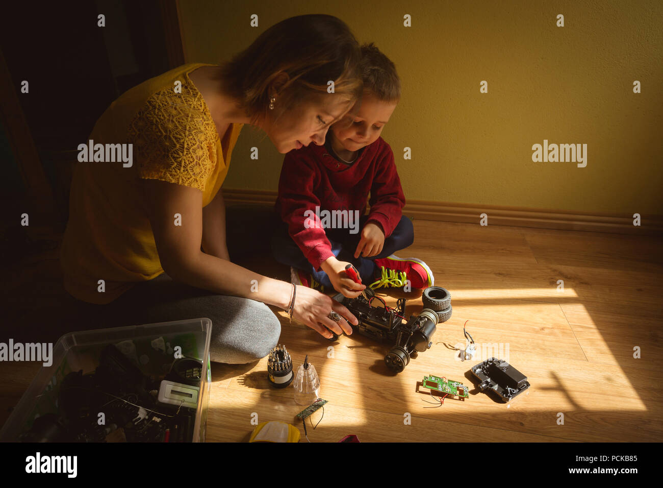 Mother and son repairing toy car in bedroom Stock Photo - Alamy
