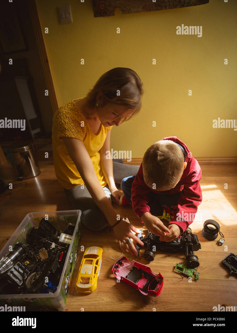 Mother and son repairing toy car in bedroom Stock Photo - Alamy