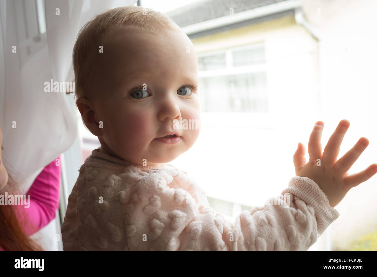 Mother with her baby girl looking through window Stock Photo - Alamy