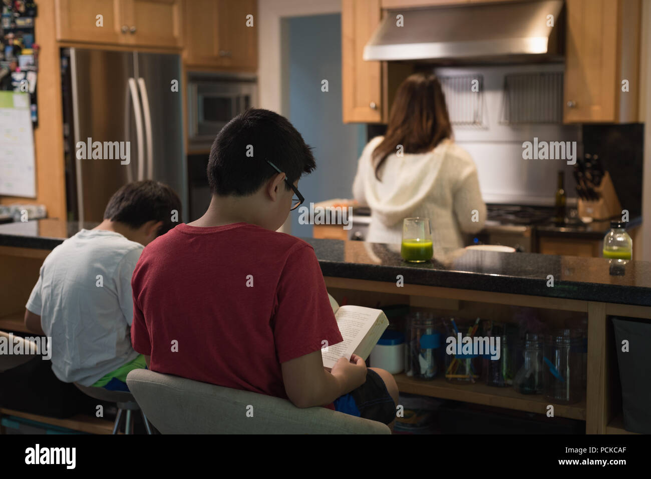 Mother cooking children studying in hi-res stock photography and images ...