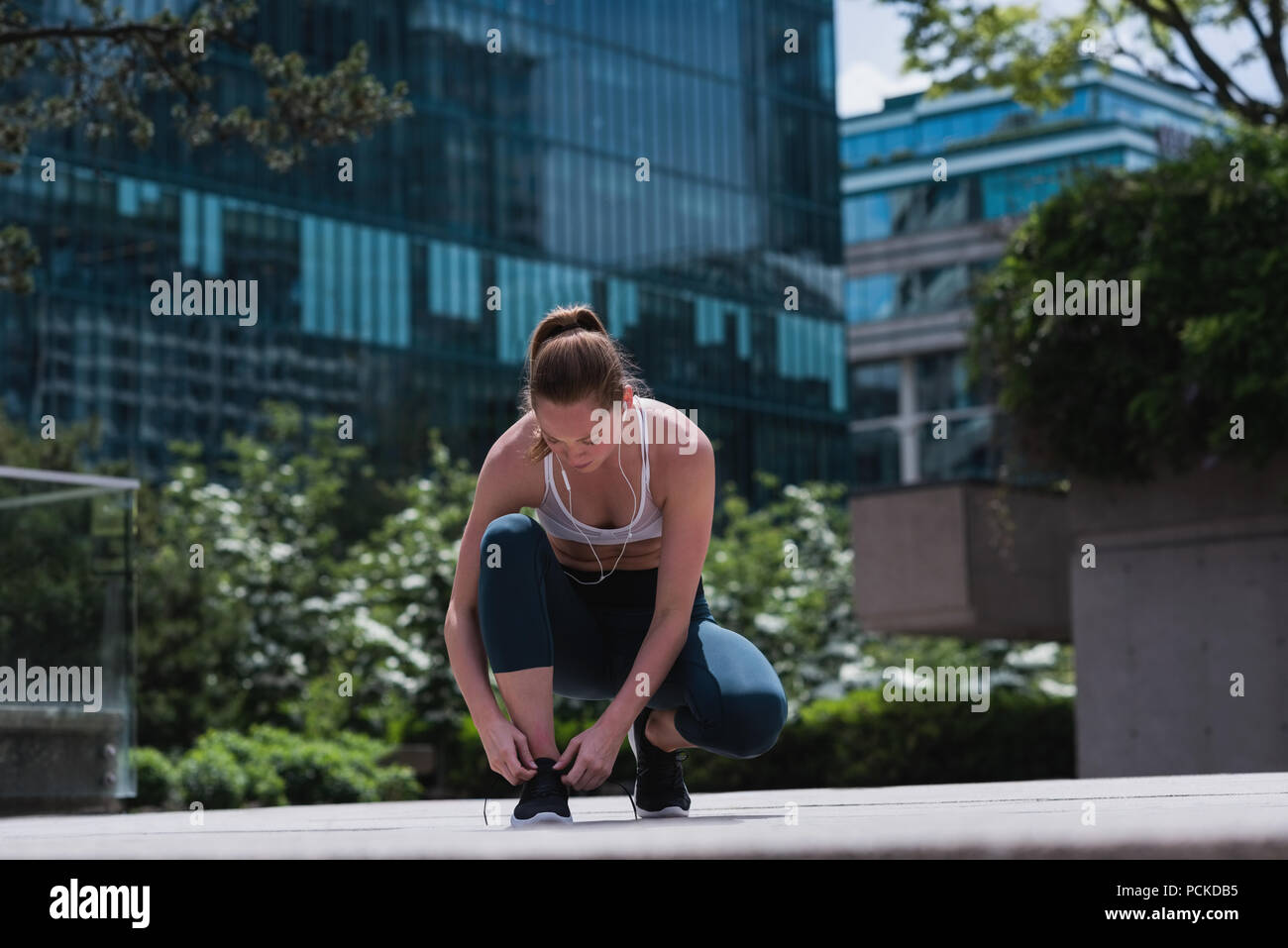 Attractive female runner tying shoe hi-res stock photography and images - Alamy
