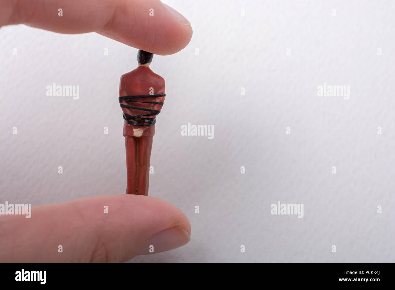 Hand holding tiny figurine of man model tied in a rope Stock Photo - Alamy