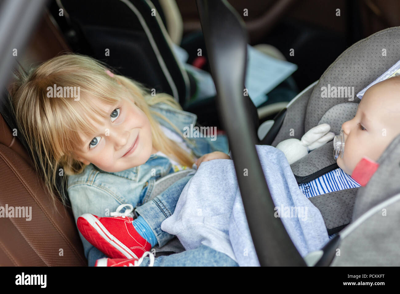 Brother and sister sitting in car in safety seat. Siblings on passenger ...