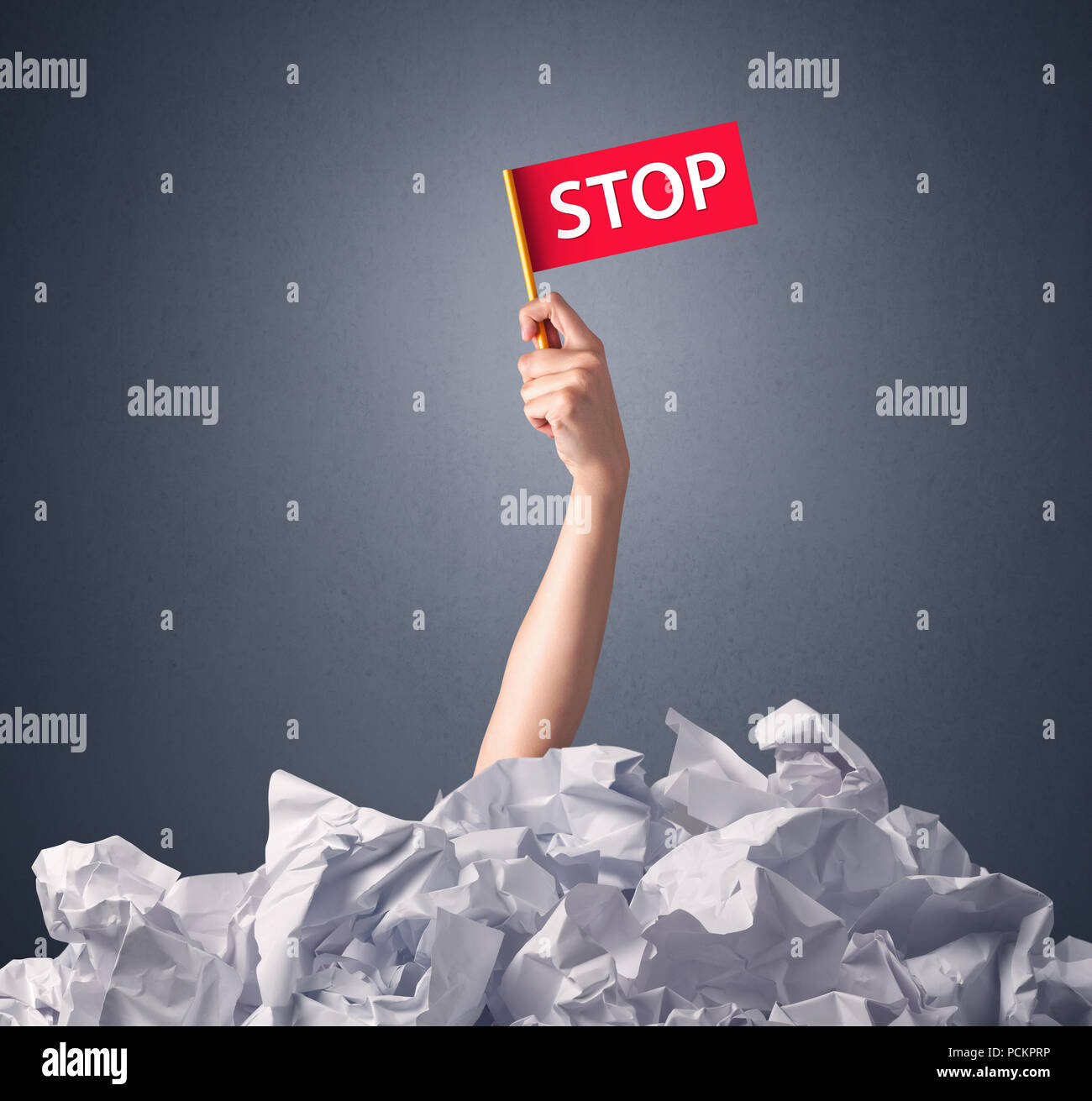 Female hand emerging from crumpled paper pile holding a red flag with ...