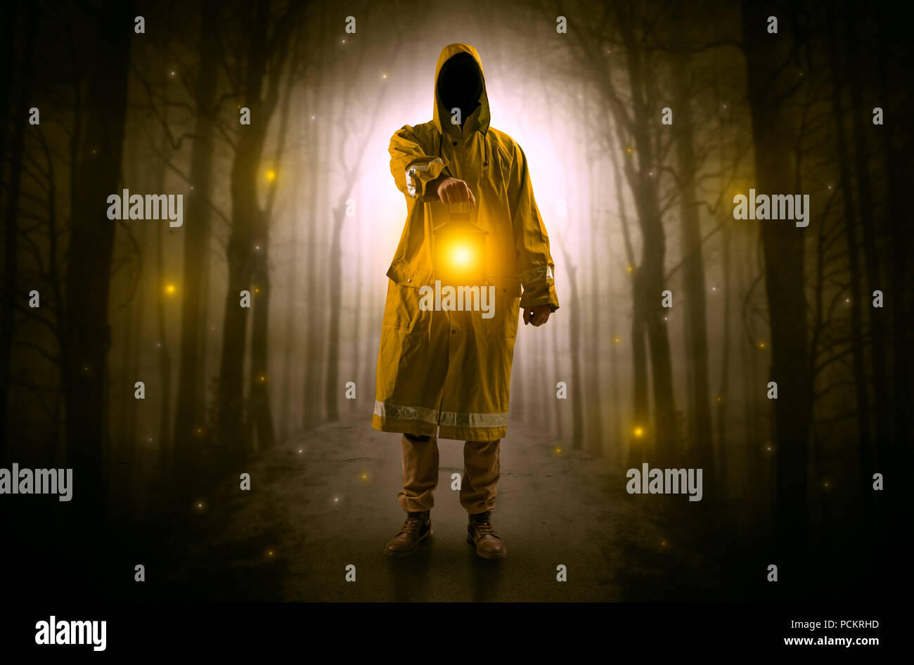 Man in raincoat coming from dark forest with glowing lantern in his ...