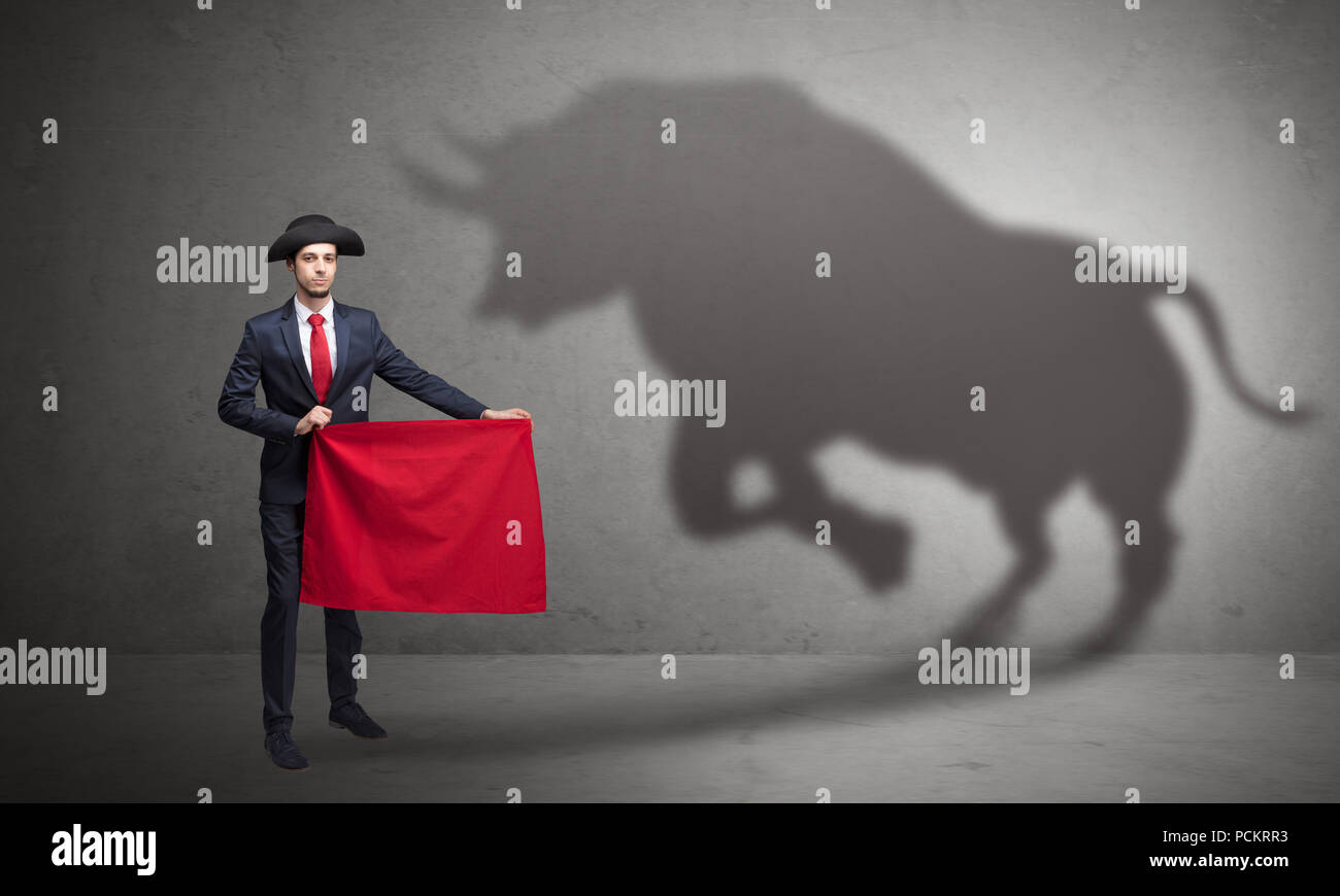 Businessman standing with red cloth in his hand and big bull shadow on ...