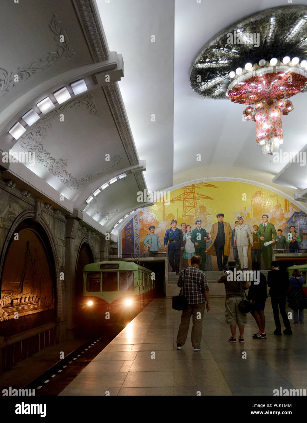 Tourists watching photographing a metro train as it arrives in the ...