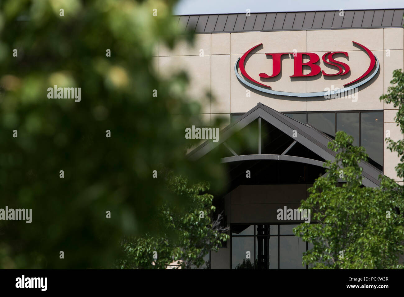 A logo sign outside of the headquarters of JBS USA Holdings, Inc., in ...