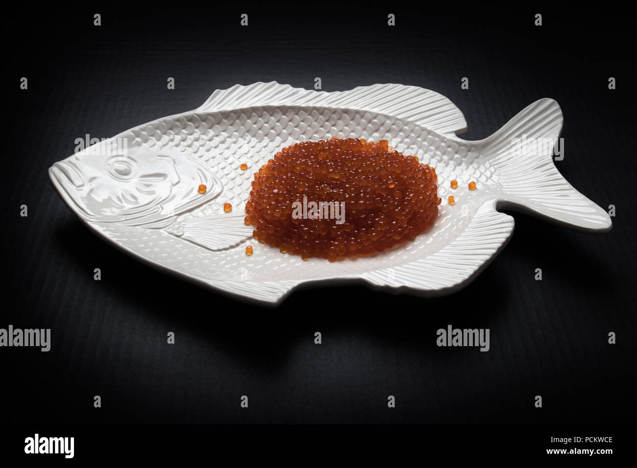 Red salmon caviar on a fish-shaped plate, isolated on black Stock Photo ...