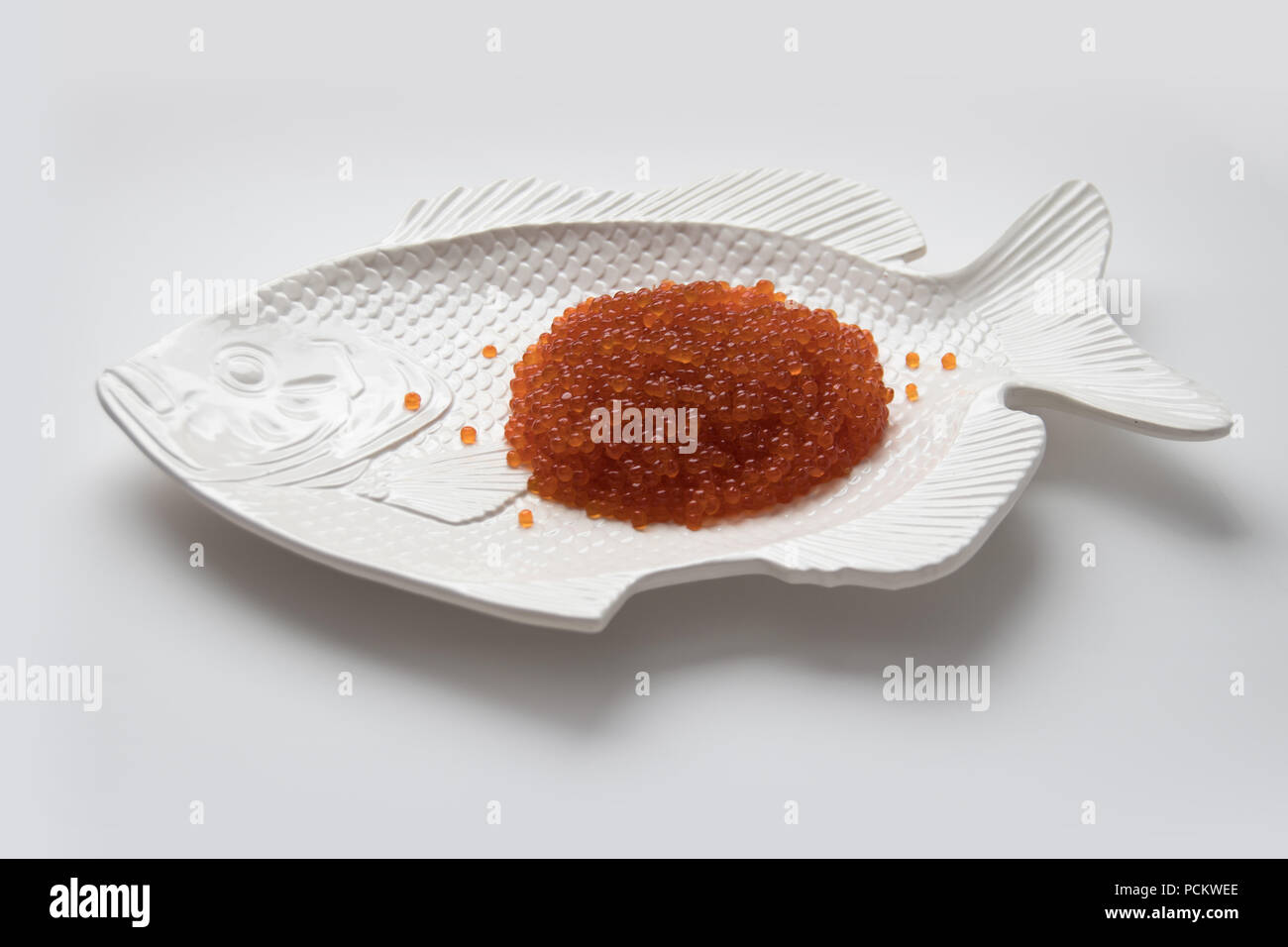 Red salmon caviar on a fish-shaped plate, isolated on white Stock Photo ...