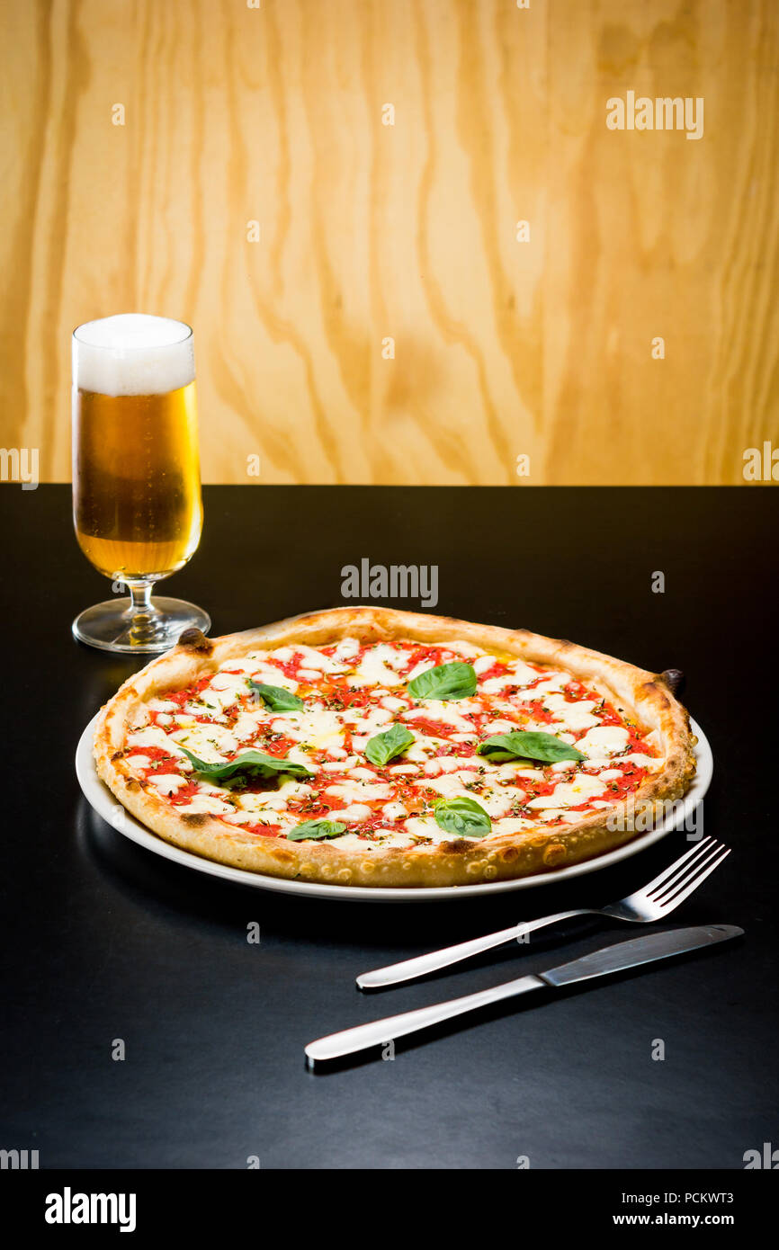 Delicious pizza served with a beer in a restaurant Stock Photo - Alamy