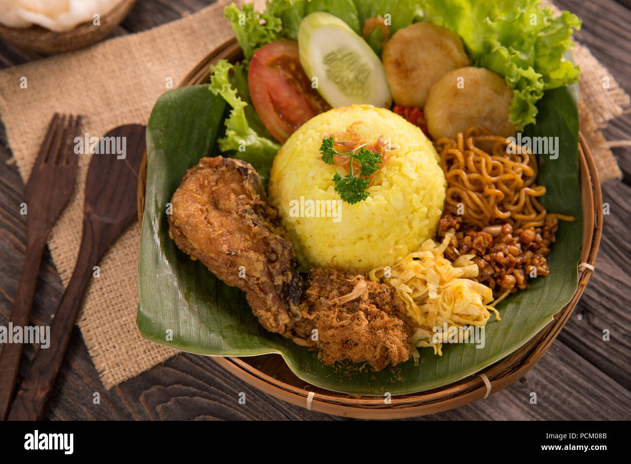 nasi kuning. indonesian yellow rice served with fried chicken on banana ...