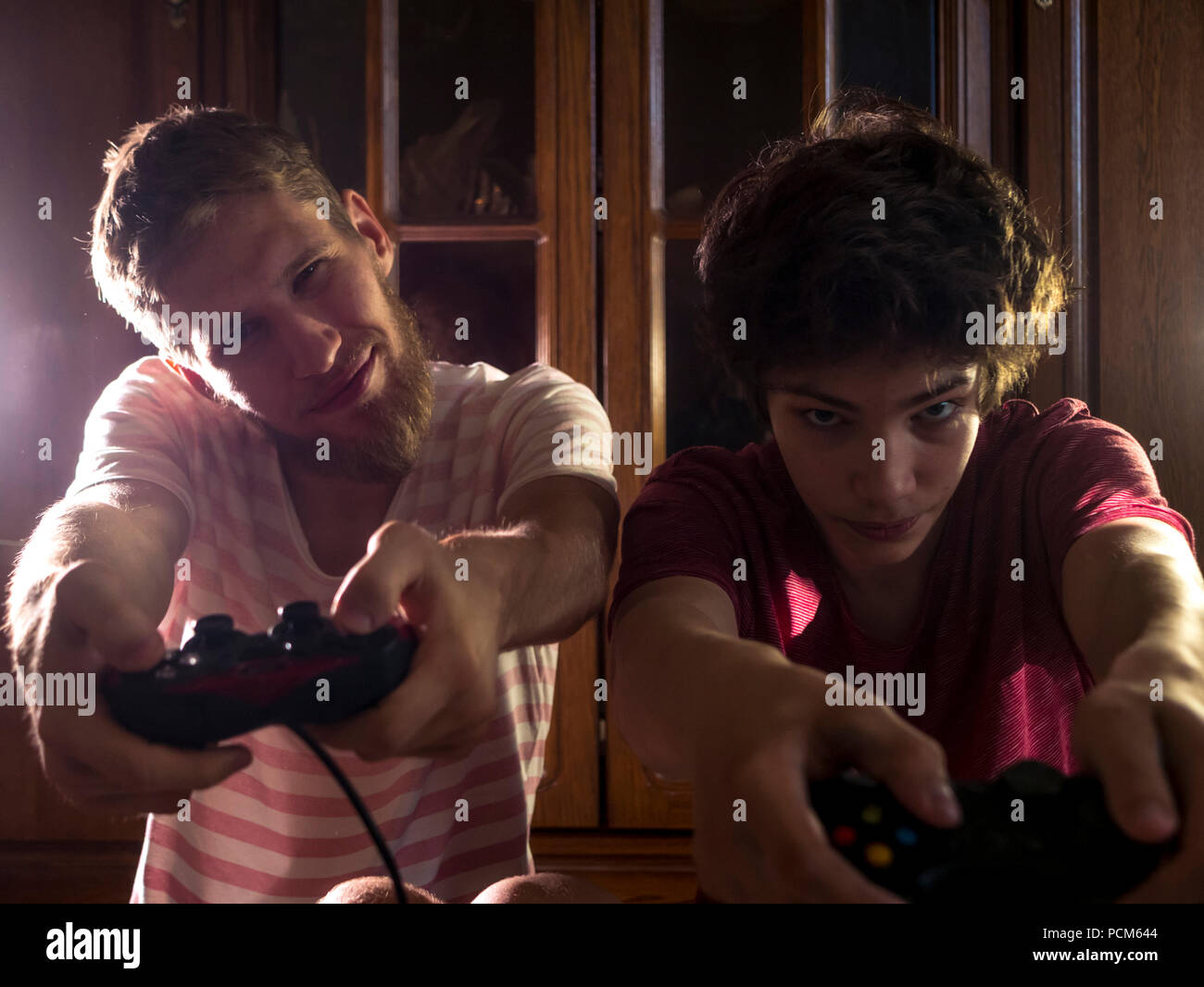 two male play console game in the night dark room with joystick gamepad ...