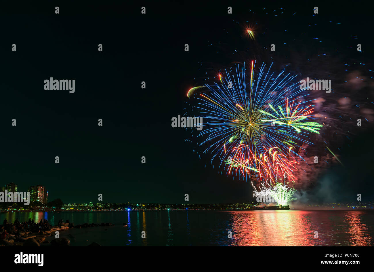 Multicolored fireworks over the ocean in the big city, silhouettes of ...