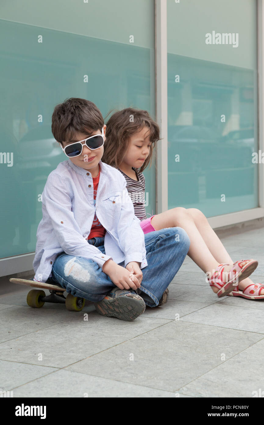 portrait of two children sitting on the sidewalk Stock Photo - Alamy
