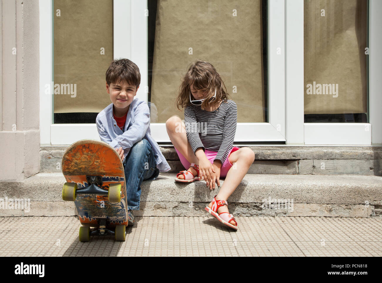 portrait of two children sitting on the sidewalk Stock Photo - Alamy