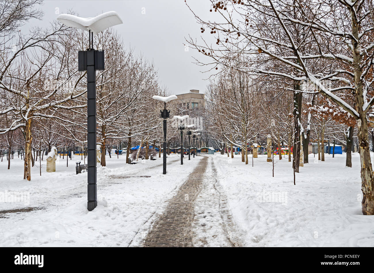 Cold January snow covered the pedestrian path in city park Stock Photo ...