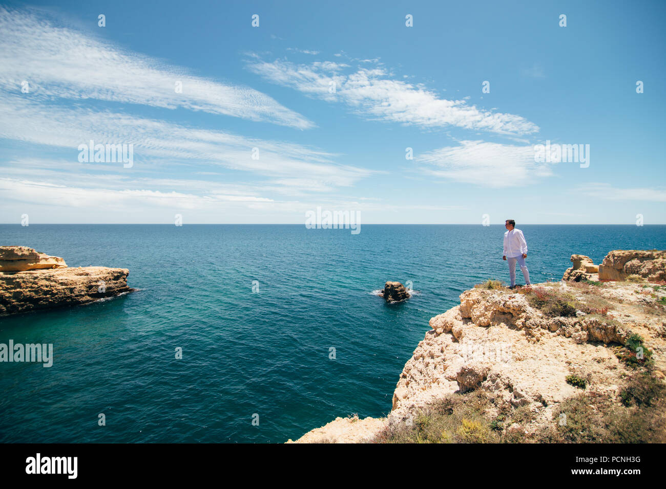 Handsome man on a cliff of ocean enjoy the view Stock Photo - Alamy