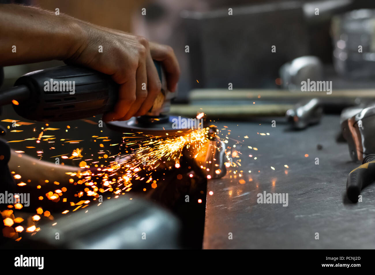 Man hands treating metal parts of hardware in a workshop with angle ...