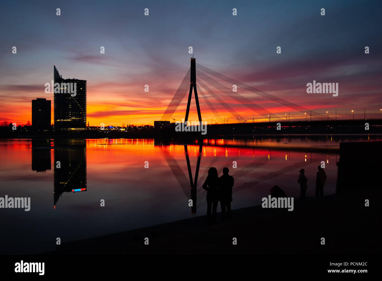 Sunset at the cable bridge on the Daugava River in Riga is watched by ...