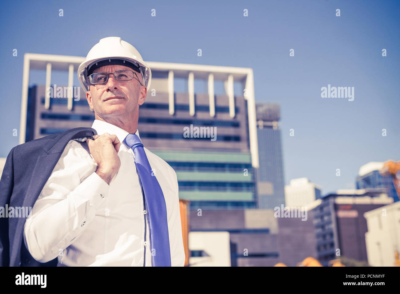 Senior elegant builder man in suit at construction site on sunny Stock ...