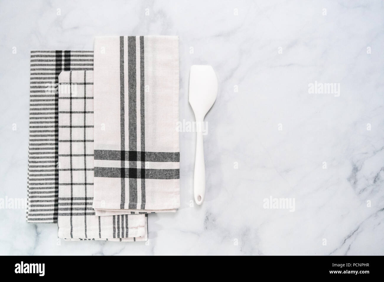 New kitchen towels with simple black pattern folded on marble counter ...