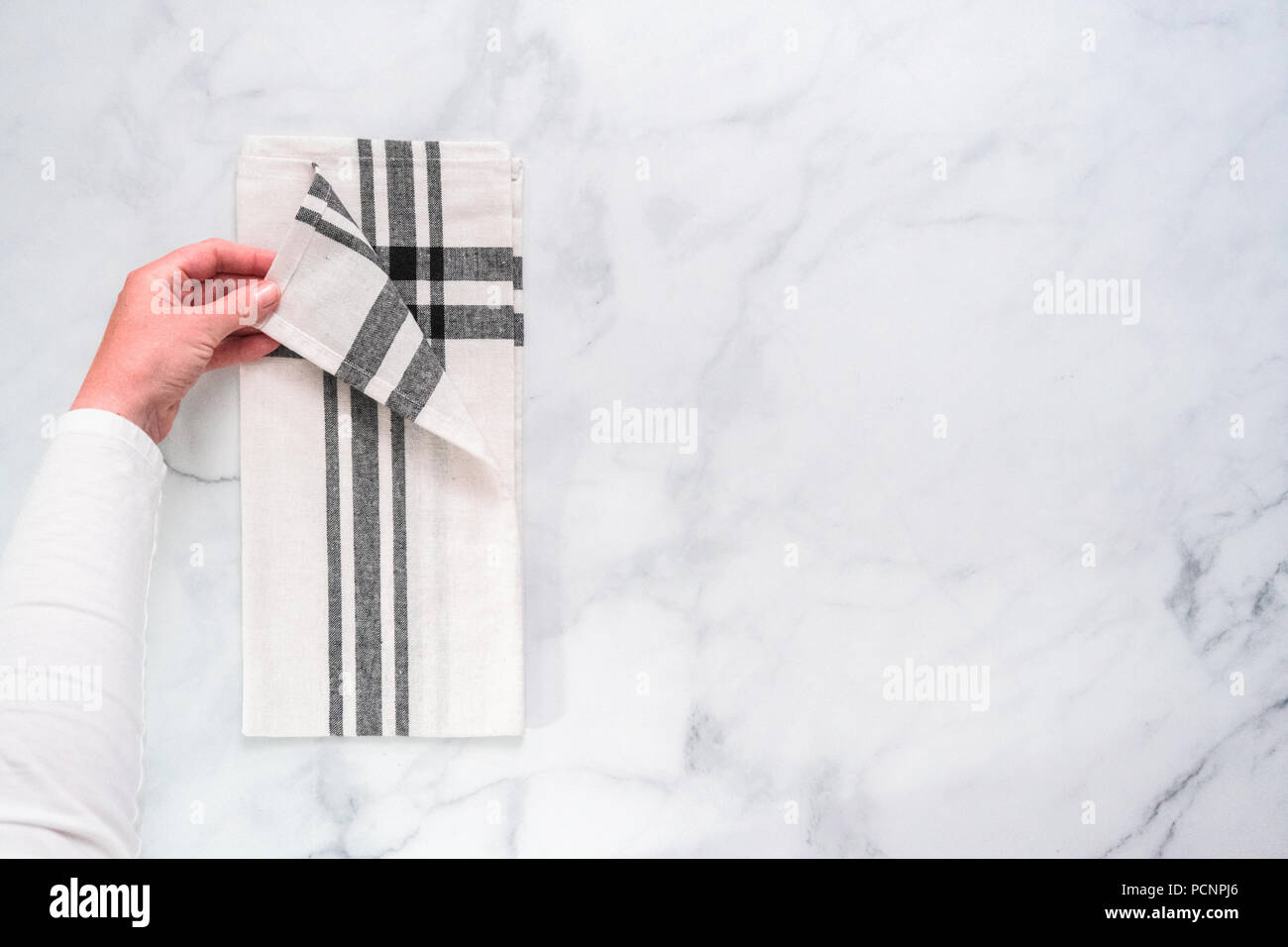 New kitchen towels with simple black pattern folded on marble counter ...